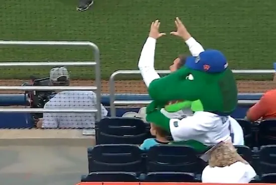 Mascotte beschermt een klein mannetje tegen een verdwaalde honkbal Mascotte beschermt een klein mannetje tegen een verdwaalde honkbal