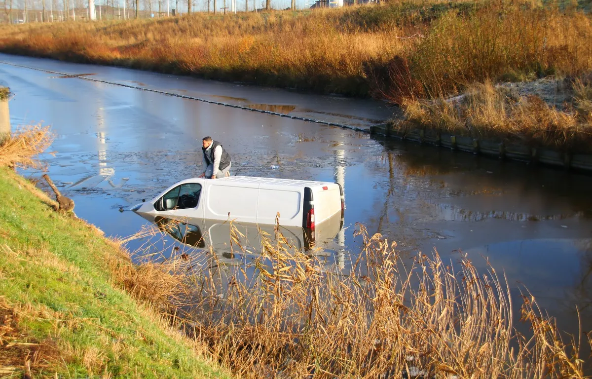 Auto te water; bestuurder wacht op dak van auto op hulp
