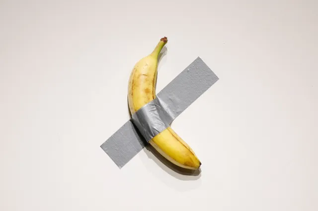 Koper eet banaan op die als kunst aan de muur was geplakt, zie beelden